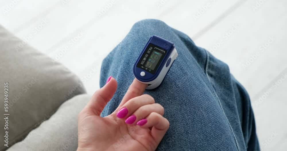 Woman measuring her pulse and oxygen levels with a pulse oximeter ...