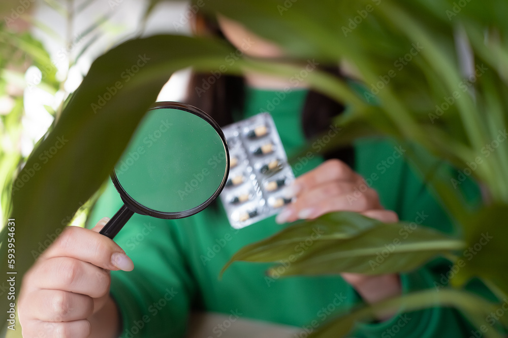 scientist with a magnifying glass checks defective medical pills ...