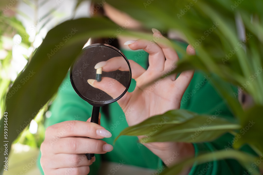 scientist with a magnifying glass checks defective medical pills ...
