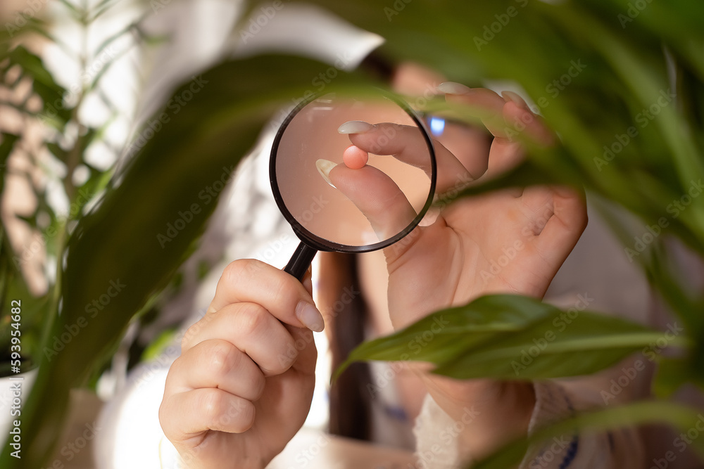 scientist with a magnifying glass checks defective medical pills ...