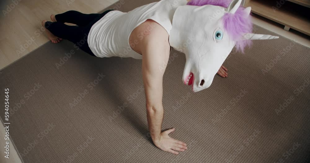 Funny man with unicorn mask doing push-up exercise at home. comical ...