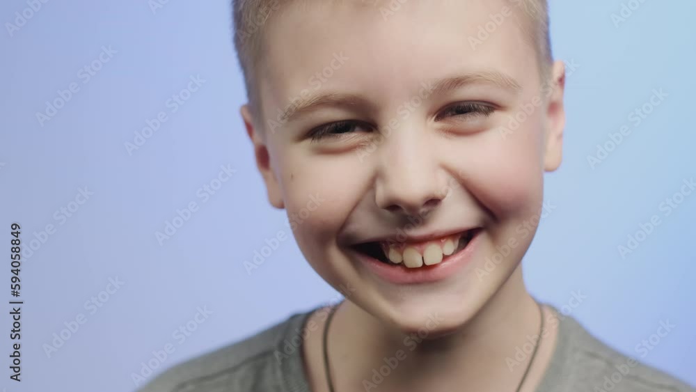 Vidéo Stock Kid laughs. Dental health concept. Caucasian boy toothy smiling on blue background ...