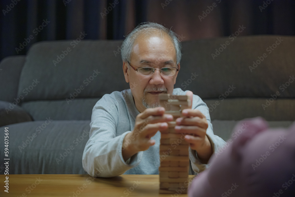Happy grandparents Asian family enjoy playing toy block with little daughter and mother together ...
