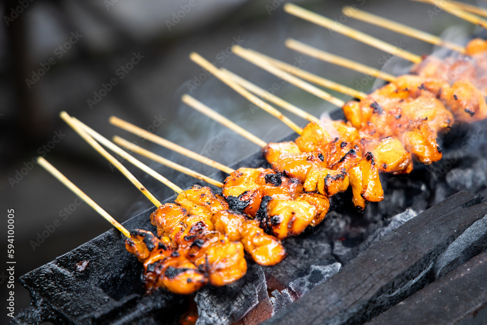 Closeup of chicken satay being barbecue with traditional pit and fired ...