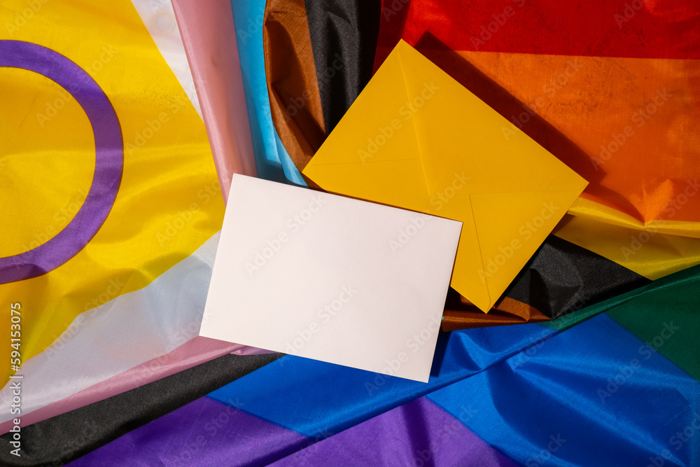 Empty paper blank on Rainbow LGBTQIA flag made from silk material. Mock ...
