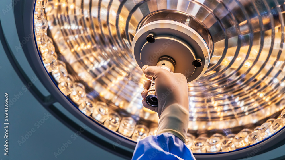 Doctor or surgeon in blue gown holding surgical lamp to adjust light ...
