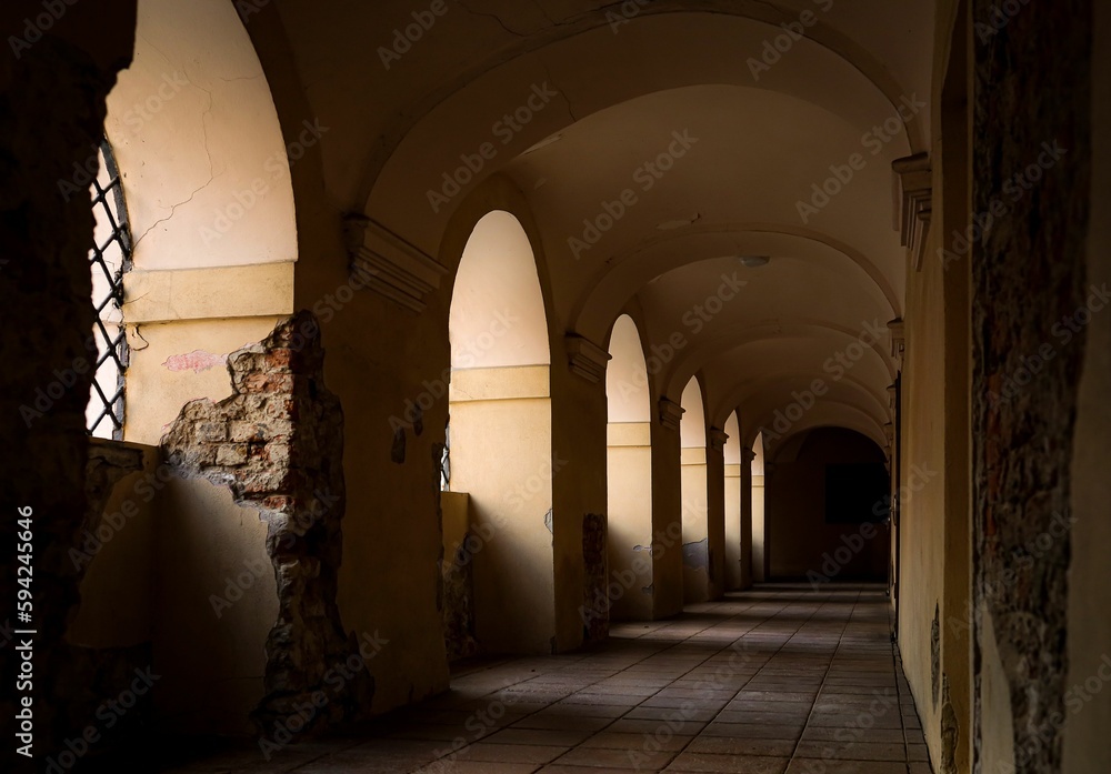Interior view of a cloister featuring a long hallway with archways and ...