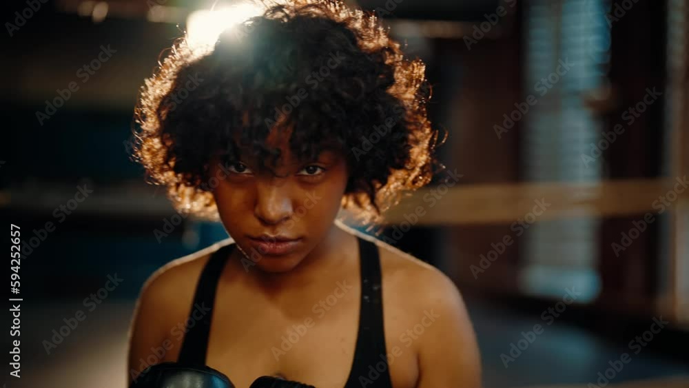Strong afro american young woman boxer in boxing pads looks at camera ...