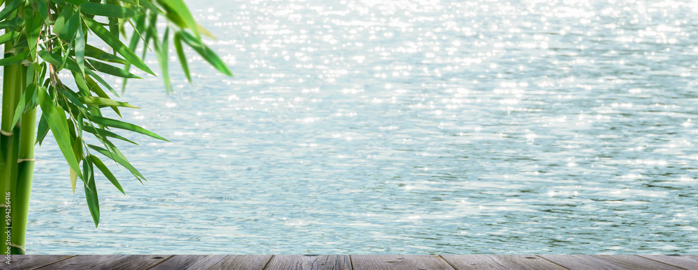 bamboo plant with empty wooden jetty in front of blurred sun lights ...
