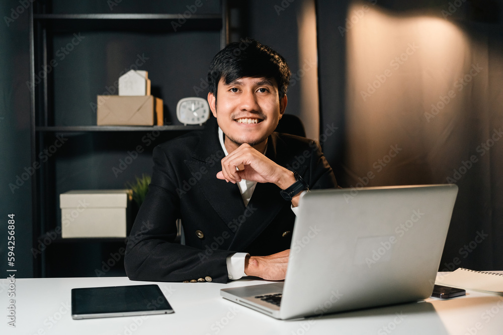 Young asian businessman working with laptop computer in the dark office ...