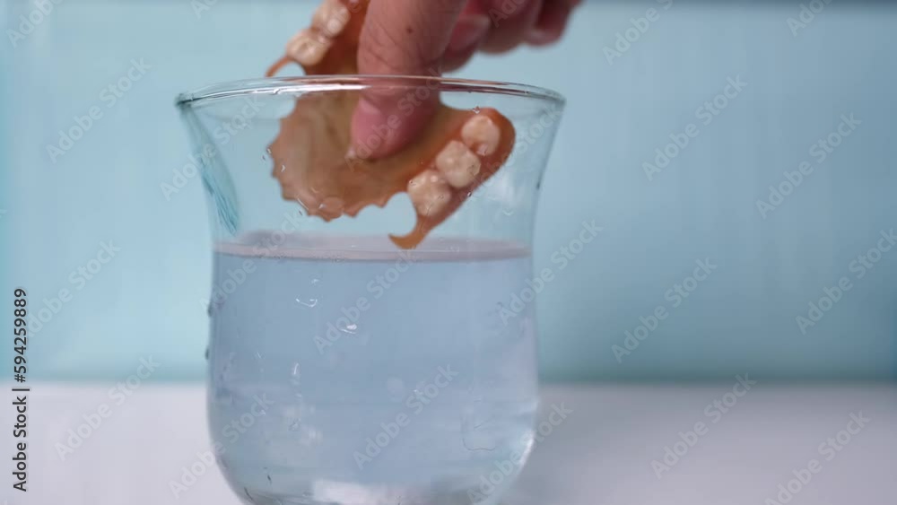 female hand close-up puts partial plastic prosthesis for the upper jaw ...