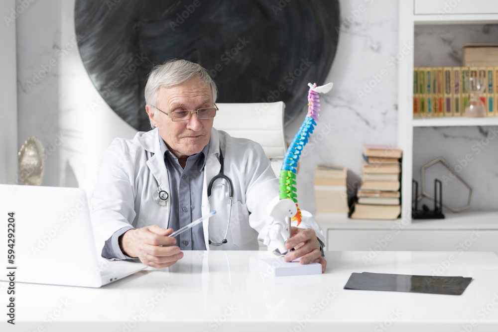 Aged male doctor orthopedist demonstrating the problem on spine bone ...