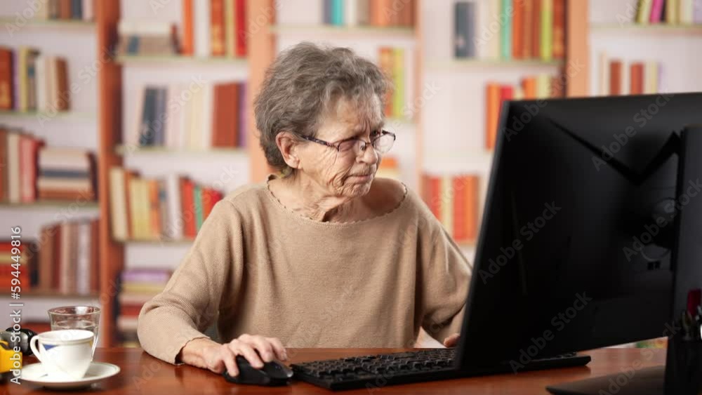 Angry stressed elderly old woman shoots computer with a toy gun. In her ...