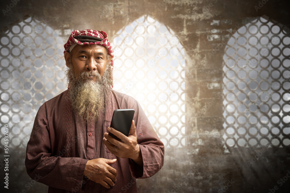 Muslim man with a beard wearing keffiyeh with agal using mobile phone ...