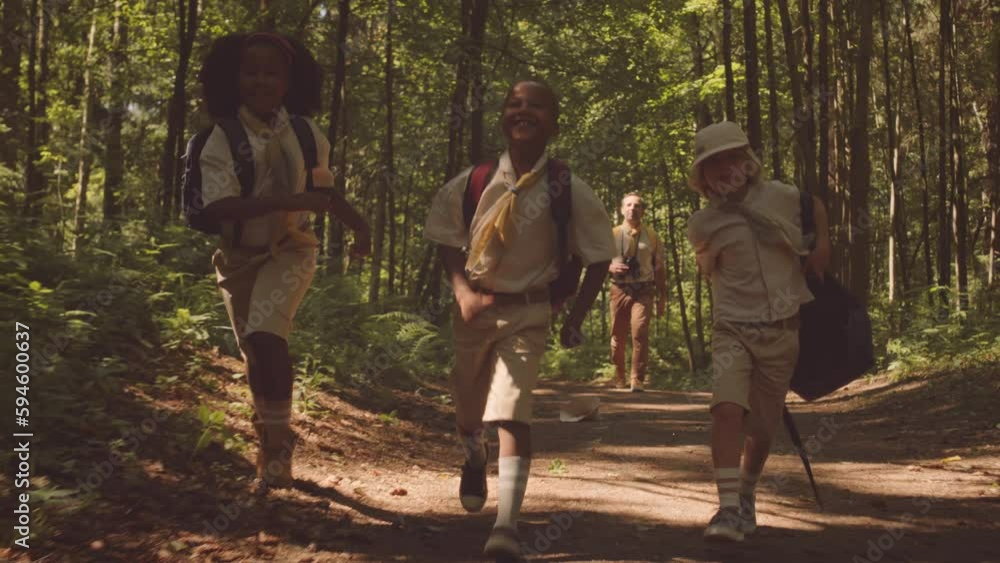 Slowmo of group of multiethnic cub scouts running along forest path ...