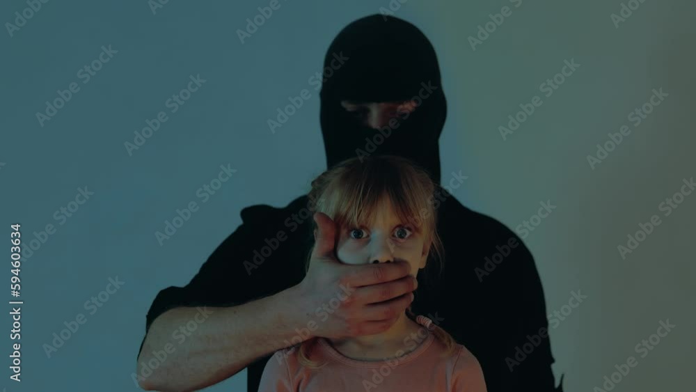 Man covering mouth of frightened kid hostage. Kidnapper in black balaclava stolen little girl ...