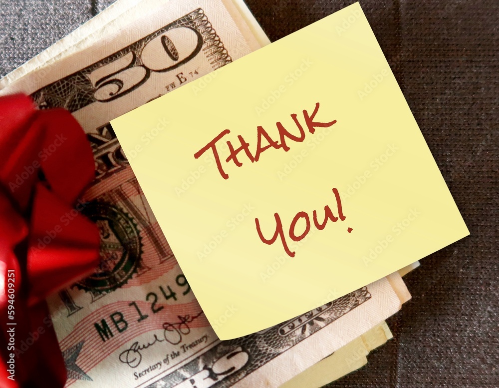 Money and red ribbon on gray background with note written THANK YOU ...