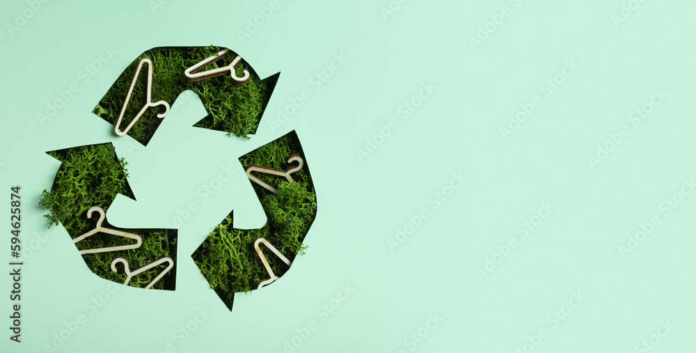 Green moss and hangers under paper cut recycling symbol. Fast fashion ...