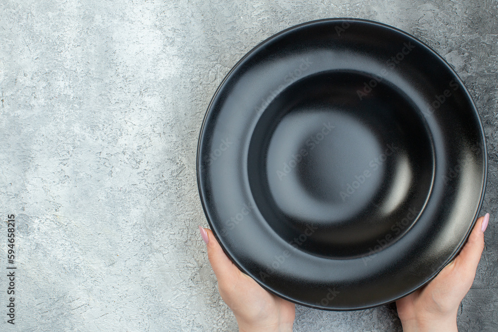 Hand holding black dinnerware set on the left side on isolated gray ice ...