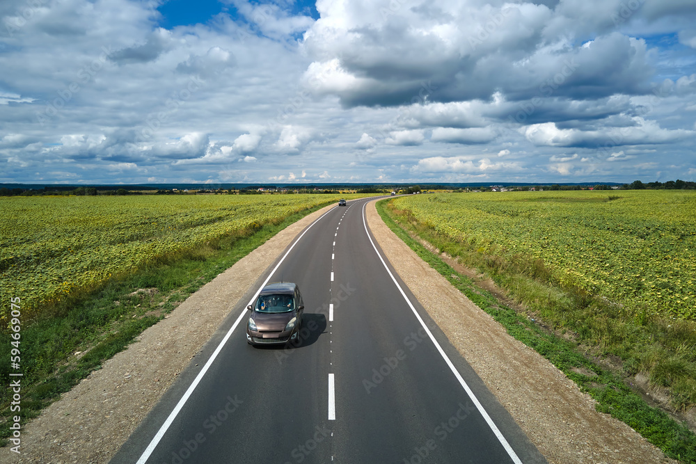 Aerial view of intercity road between green agricultural fields with ...