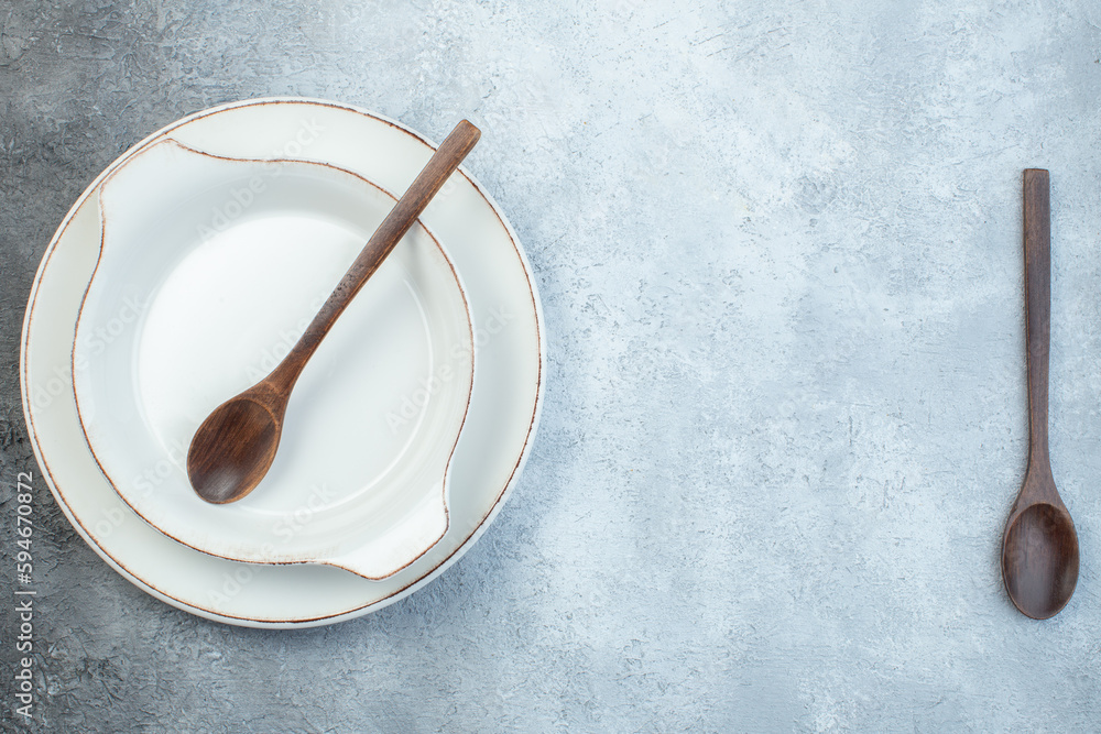Wooden spoons and empty soup plates on half dark light gray background ...