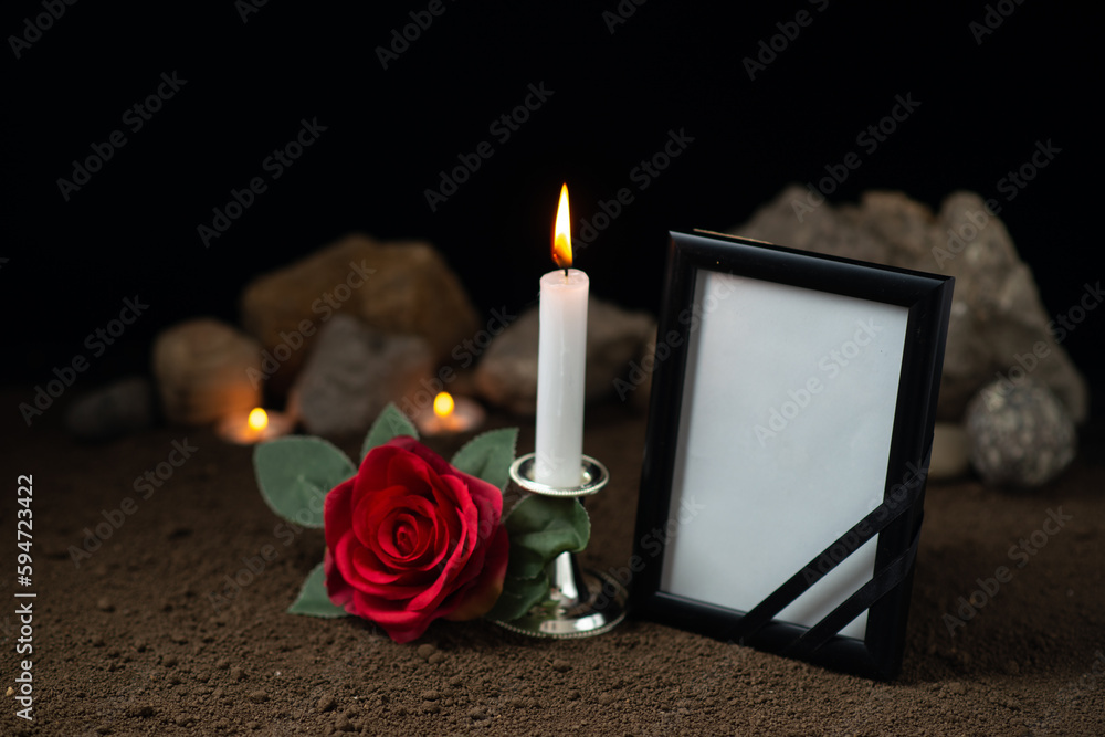 burning candle with empty picture frame and red rose on dark desk sci ...