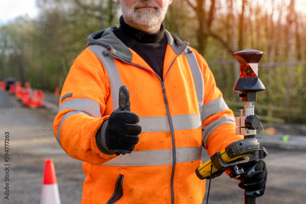 Site engineer operating his instrument during roadworks. Builder using ...