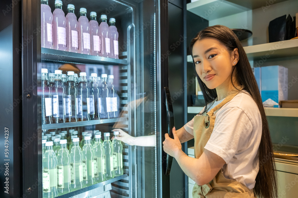 Coffee shop employee reaching for a bottle in the fridge Stock Photo ...