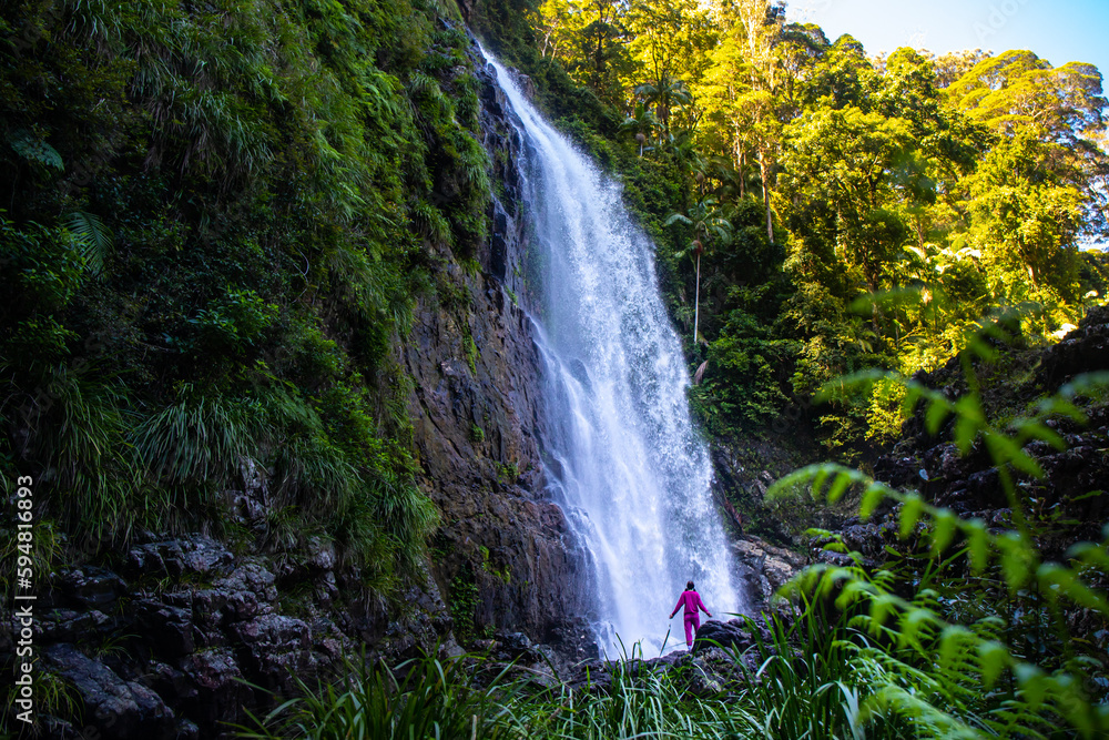 hiker girl standing in front of large tropical waterfall in australian ...