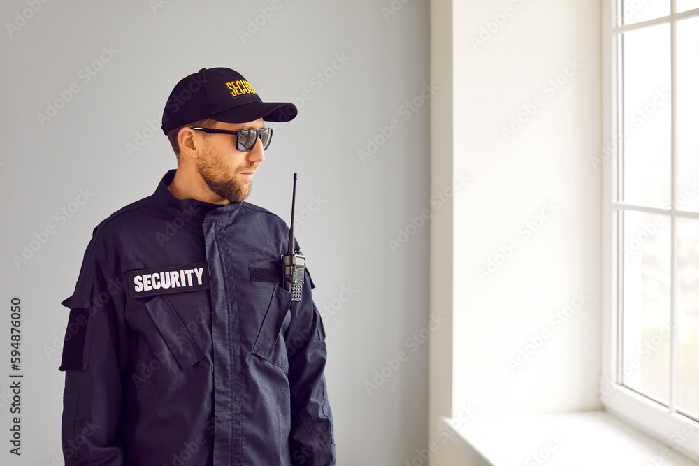 Confident security guard man in black sunglasses, uniform cap and ...