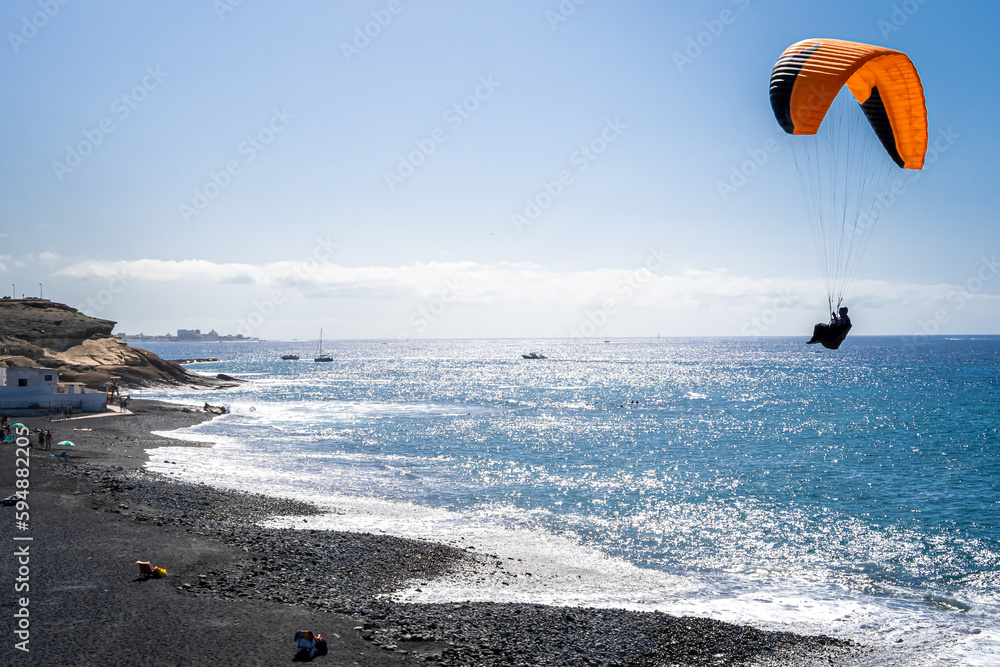 Unrecognizable paraglider lands on the Playa de la Enramada beach, a ...