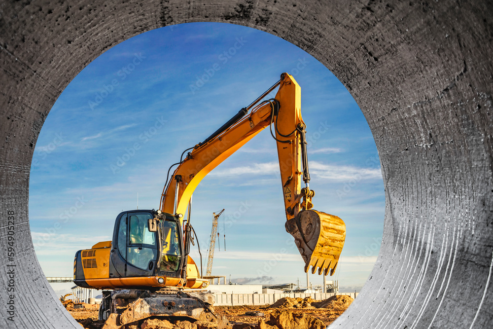 A wheeled excavator in a trench digs the ground. An excavator with a ...