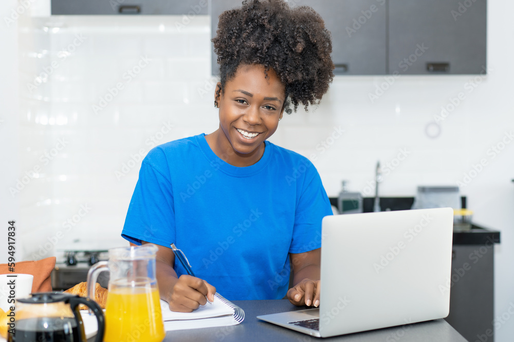 Pretty black woman with computer writing notes Stock Photo | Adobe Stock