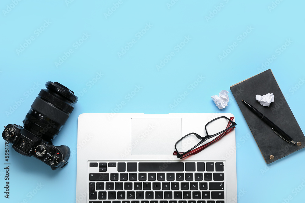 Laptop with eyeglasses, notebook and photo camera on blue background ...
