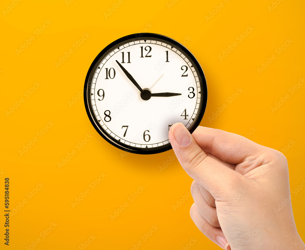 Hand holding small clock on yellow background Stock Photo | Adobe Stock