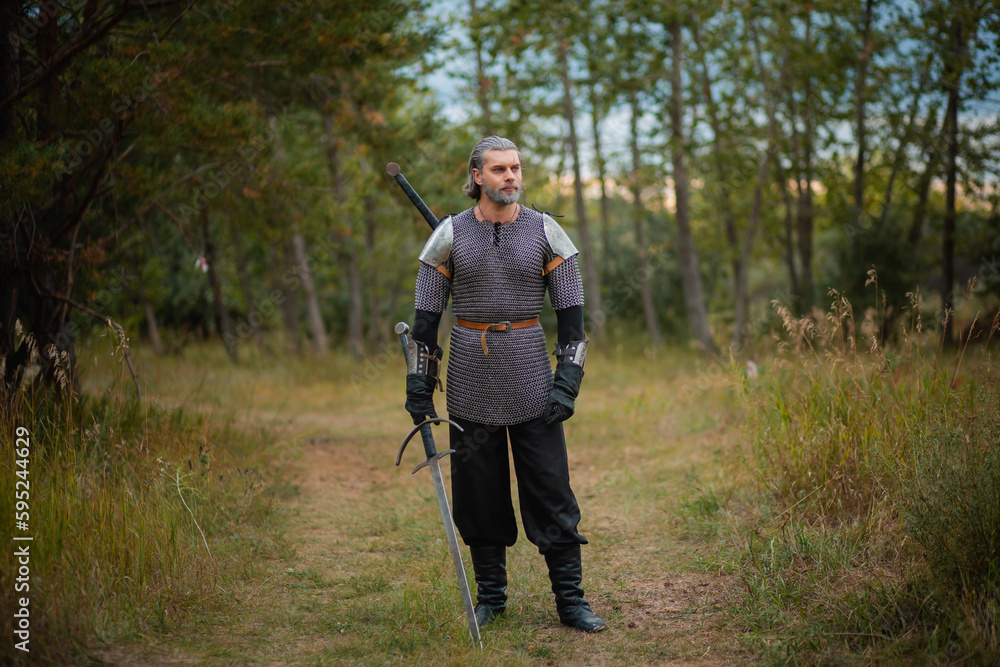 an old warrior in chain mail with a sword is looking for prey in the ...