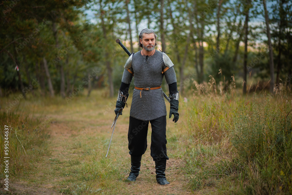 an old warrior in chain mail with a sword is looking for prey in the ...