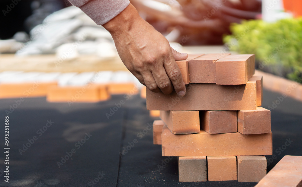 Portrait of bricklayer laying slabs and pavement in garden by workman ...