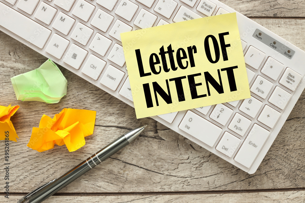 LETTER OF INTENT text on yellow sticky note and work desk with white ...
