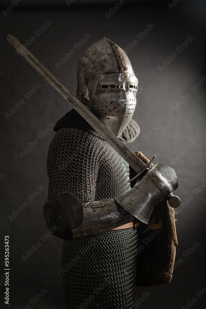 Knight with a helmet in iron armor with a shield and a sword on a black ...