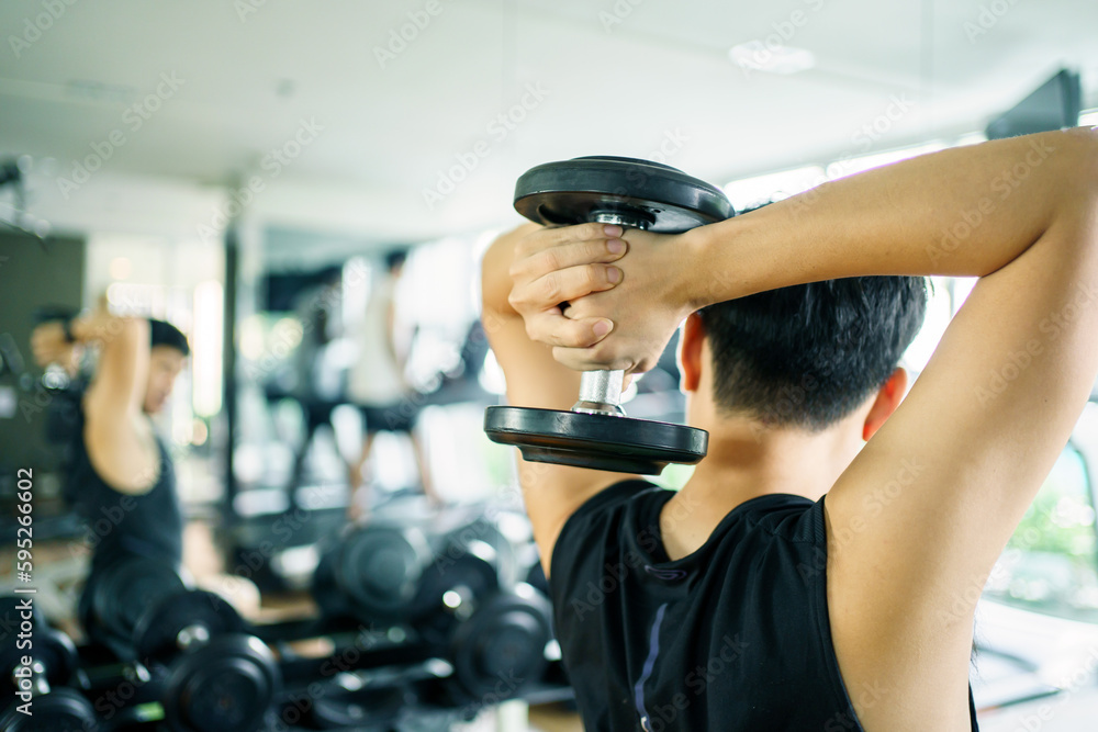 Active Asian sportsman doing a weight training exercise by lifting up a ...