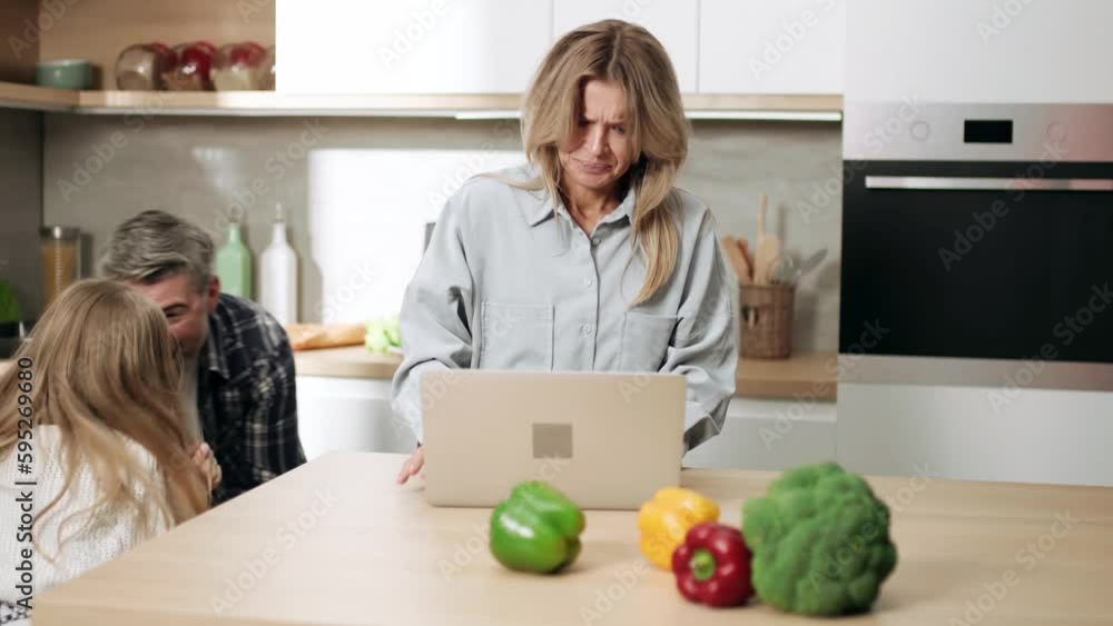 Busy nervous mature woman working on laptop computer while his family ...