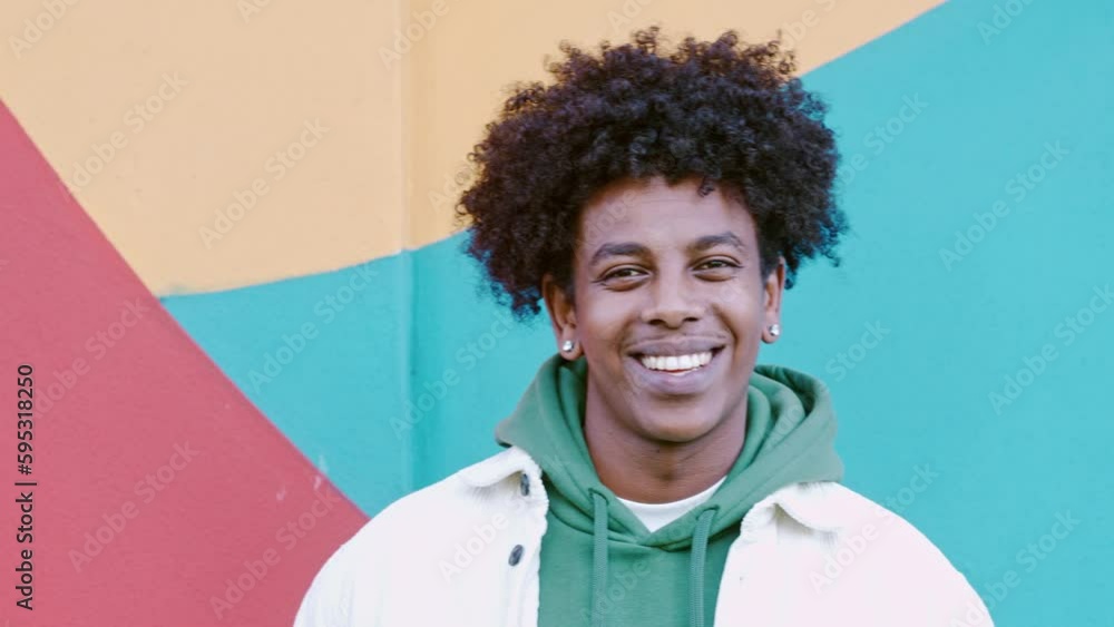 Young happy African American teen guy laughing on colorful wall ...