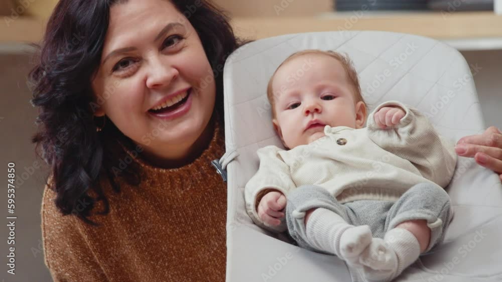 Smiling caucasian senior woman rocking cradle with adorable newborn ...