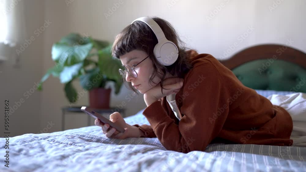 Scrolling addiction. Hipster girl wearing headphones looking at ...