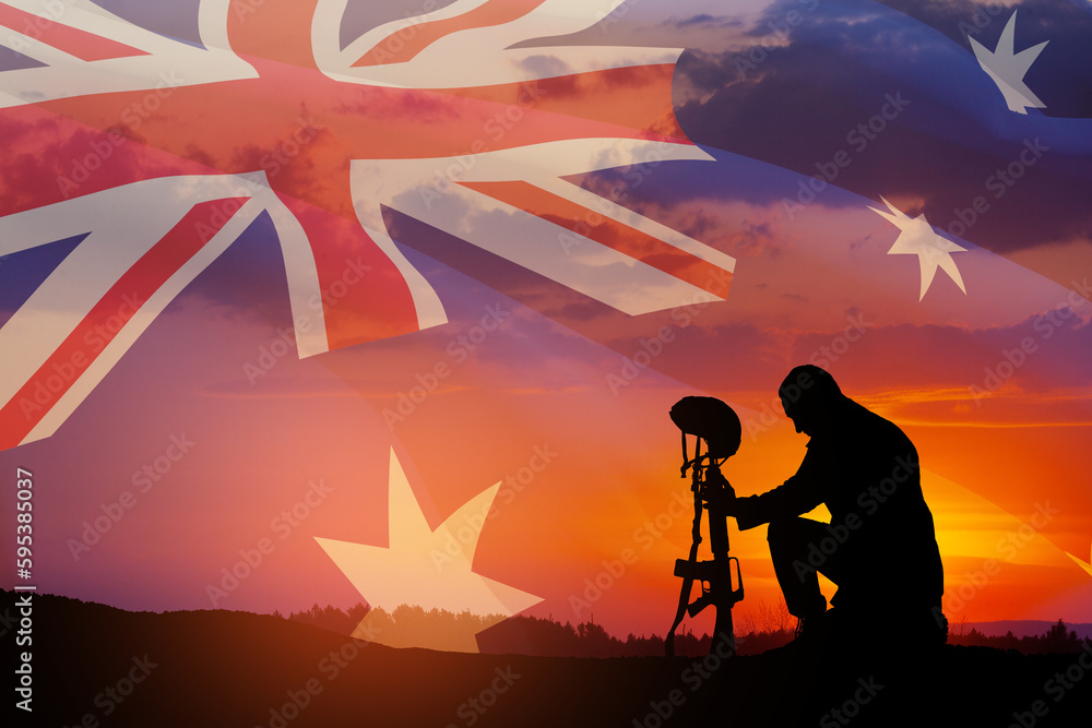 Silhouette of soldier kneeling with his head bowed against the sunrise ...