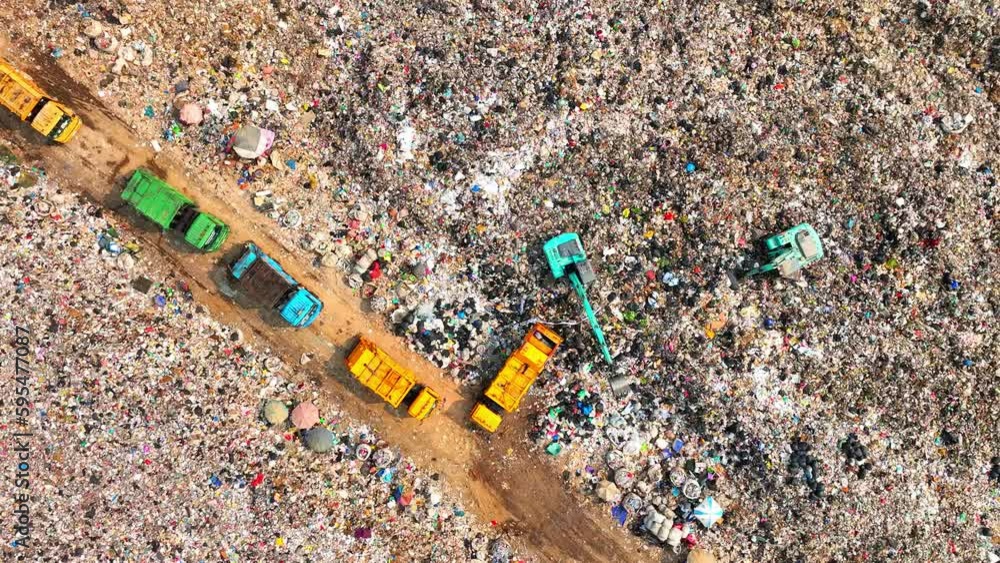 Garbage piles are cleared using excavators to load waste onto trucks ...