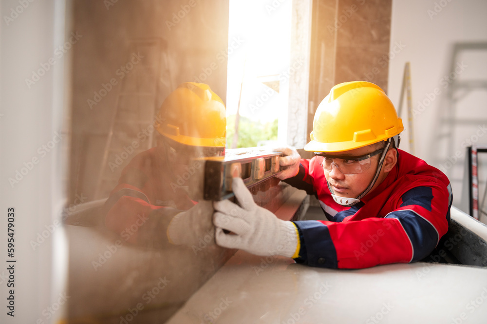 Asian worker using a level gauge to measure wall masonry working with ...