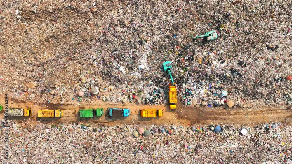 Garbage piles are cleared using excavators to scoop and load waste onto ...