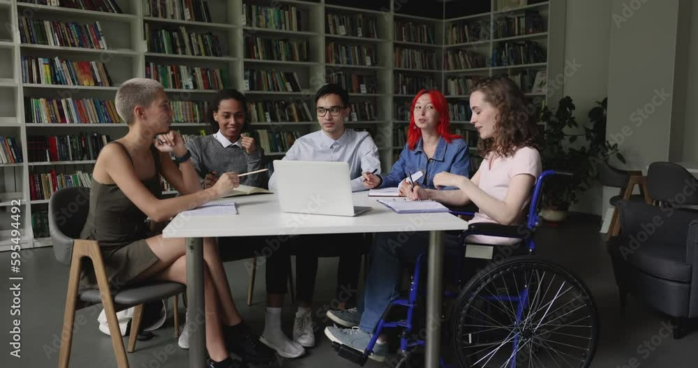 Pretty teenage student girl seated in wheelchair engaged in study ...